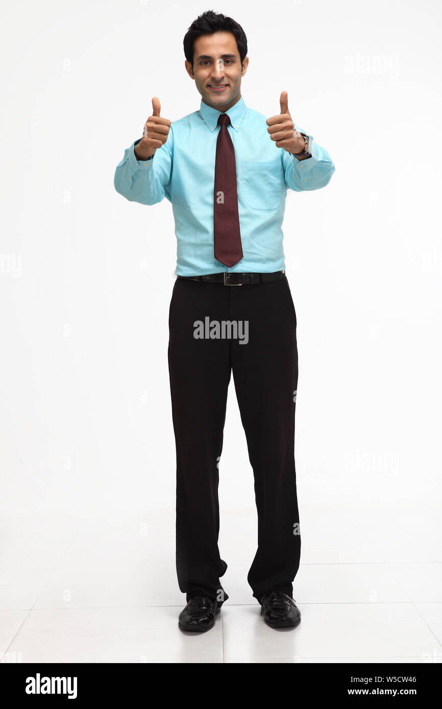 Businessman standing and showing thumbs up sign Stock Photo - Alamy