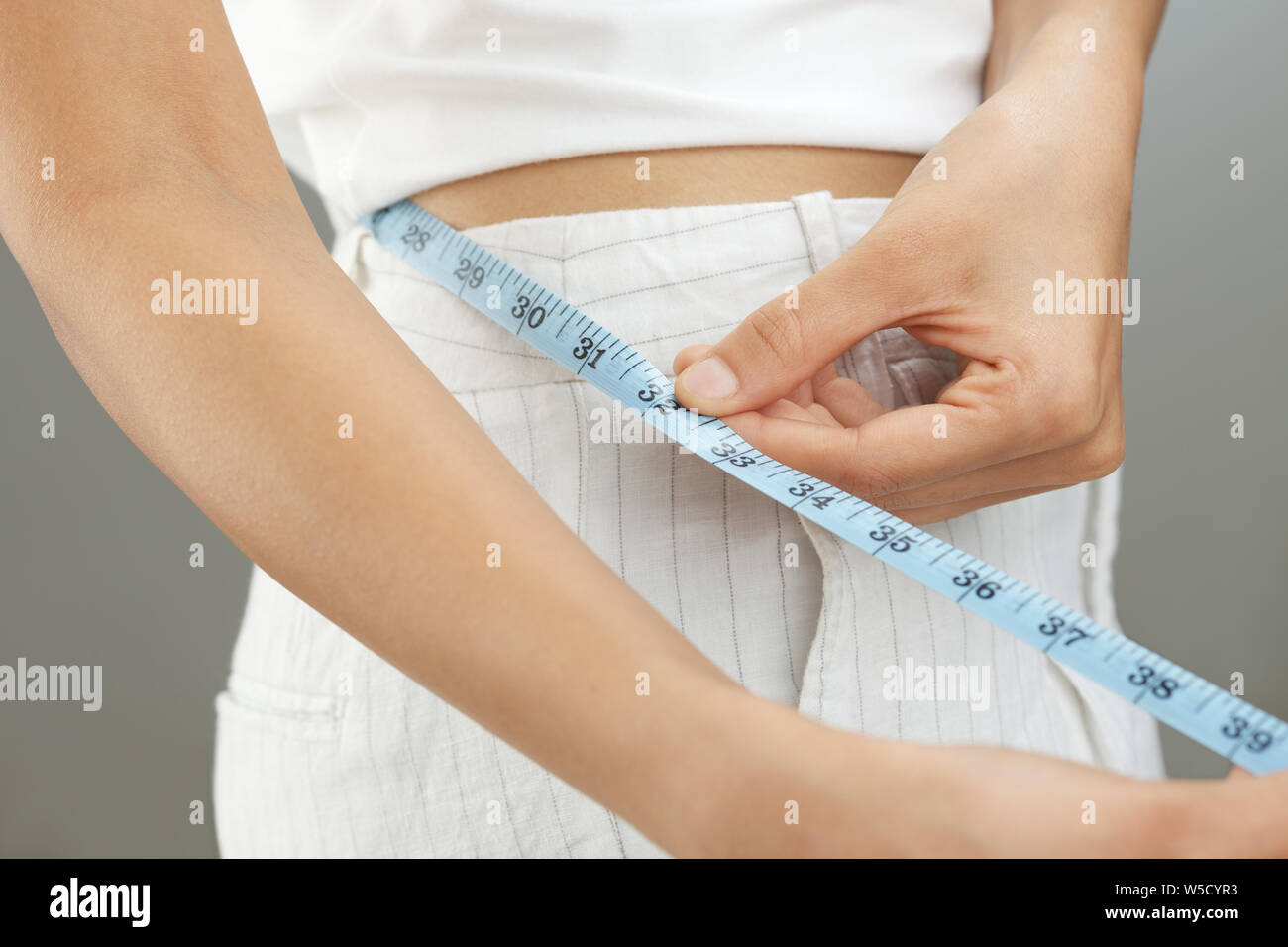 Mid section of an Indian woman measuring her waist Stock Photo - Alamy