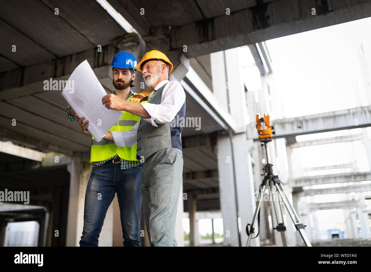 Engineer, foreman and worker discussing in building construction site ...