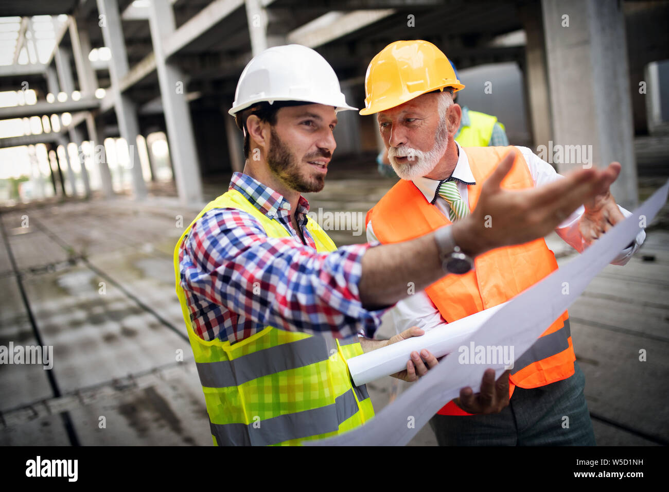 Engineer, foreman and worker discussing in building construction site ...