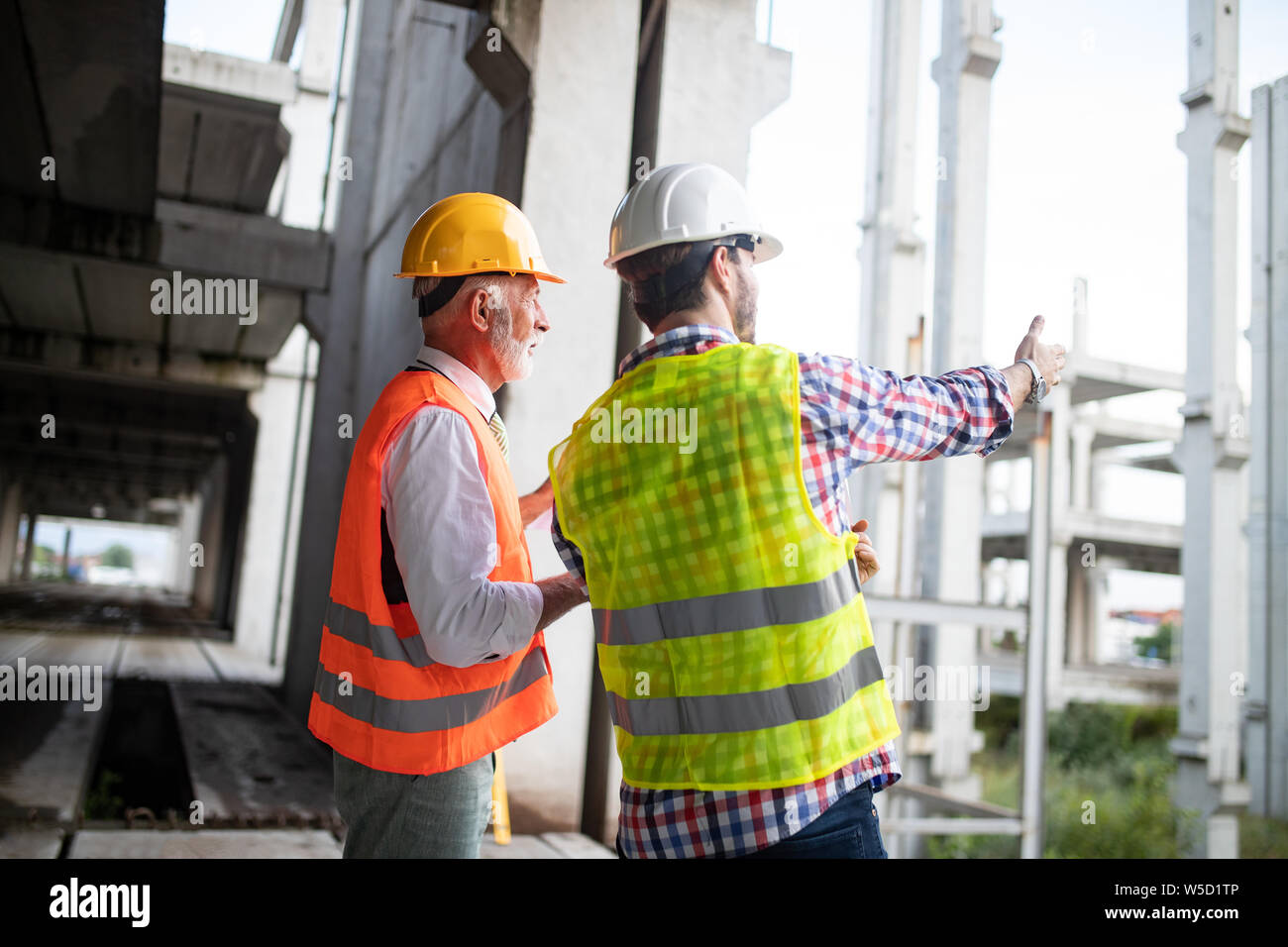 Engineer, foreman and worker discussing in building construction site ...