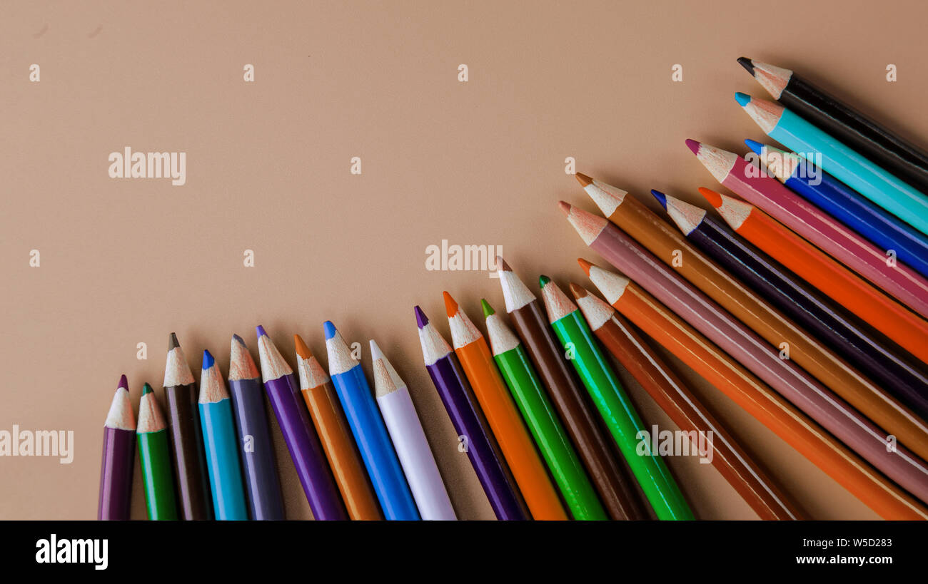 Color pencils on light pink background, school supplies Stock Photo - Alamy