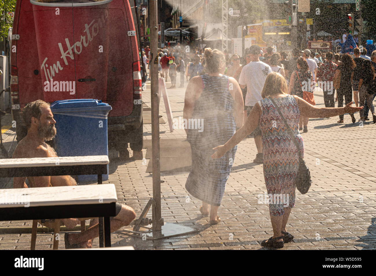 Montreal, CA - 27 July 2019: People walking under misting system to ...