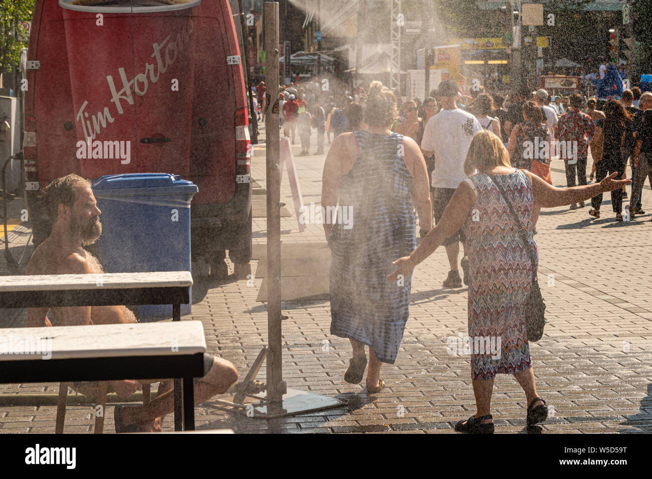Montreal, CA - 27 July 2019: People walking under misting system to ...