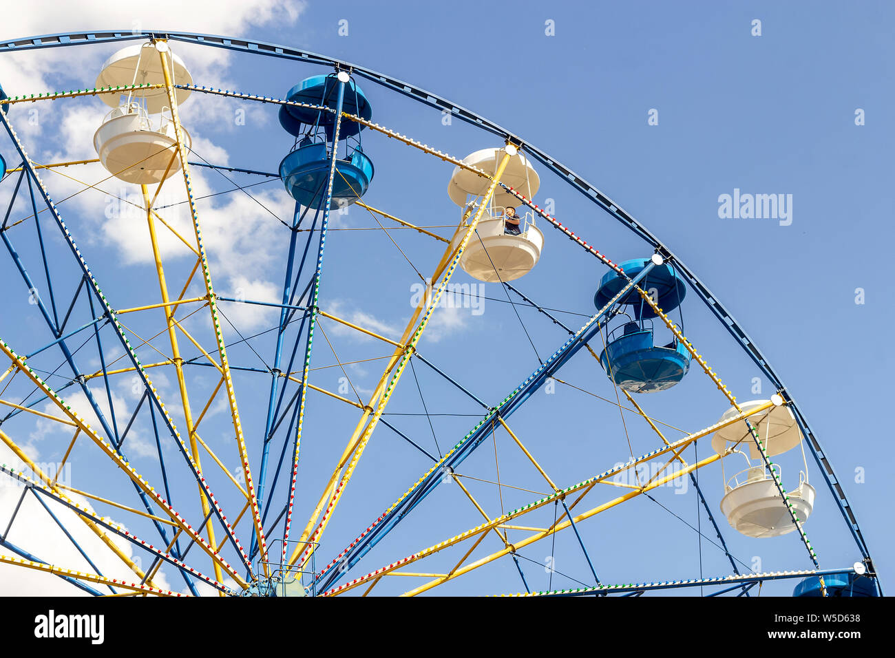 Ferris wheel close up against the blue sky and clouds. Amusement park ...