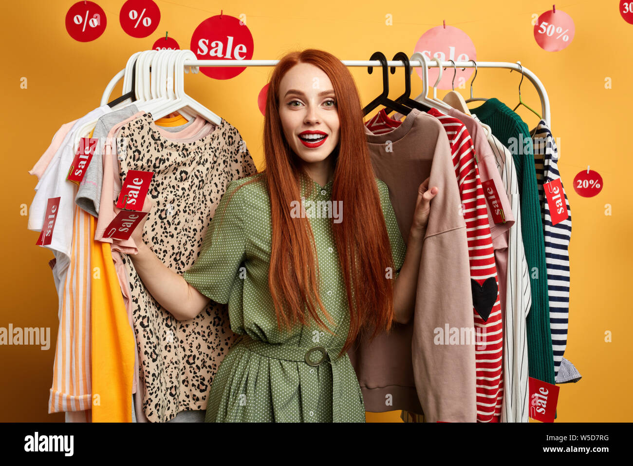 ginger stylish positive girl choosing clothes in the mall. close up ...