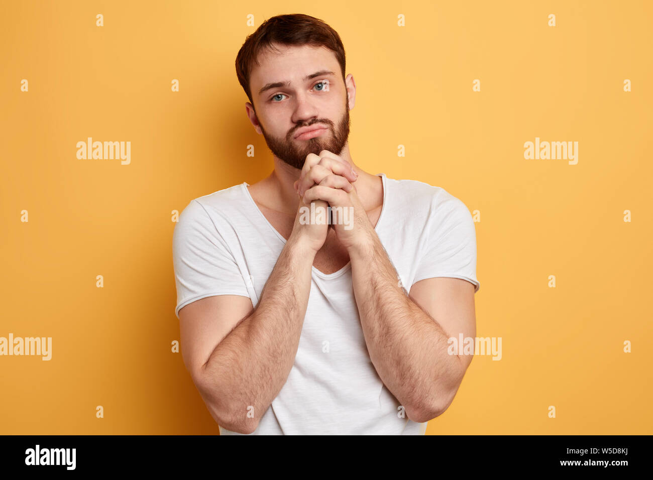 sad unhappy emotional men standing with his hands clasped and looking ...