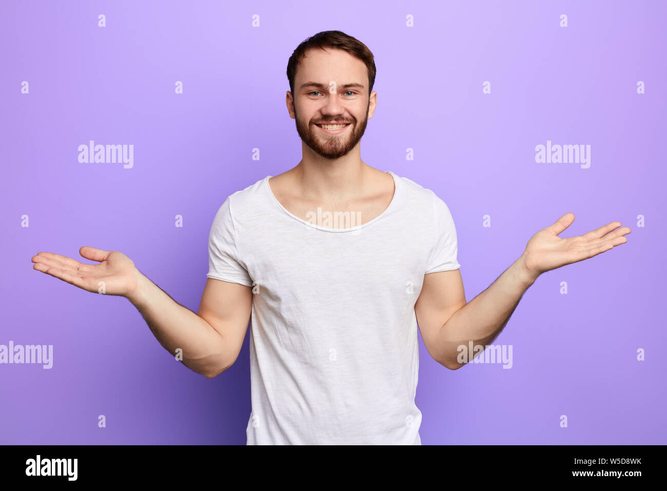 young cheerful happy handsome guy raising his hands with open palms ...
