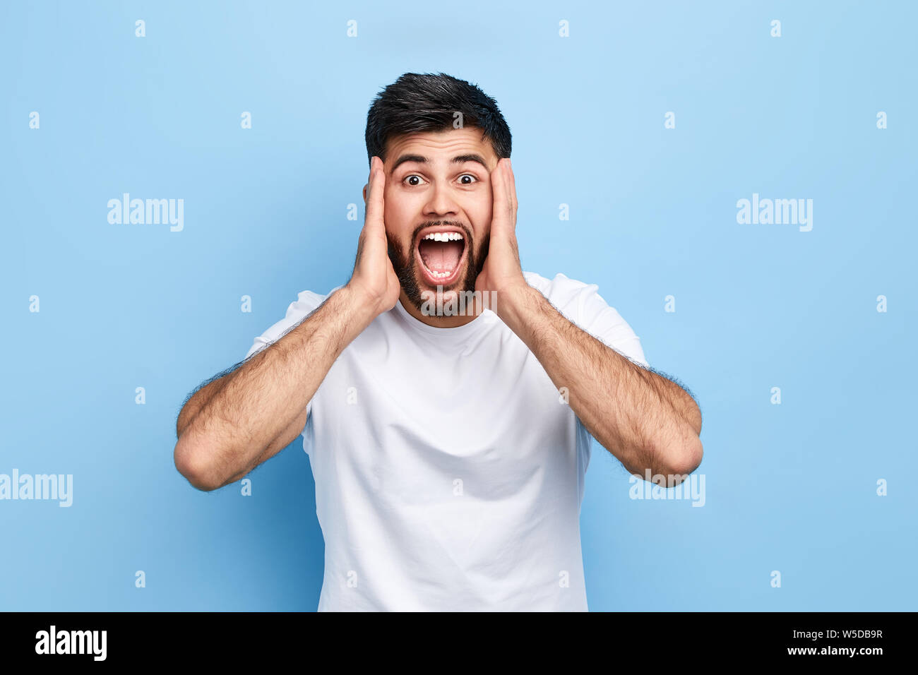 disappointed confused man touches his cheeks with palms, expresses ...