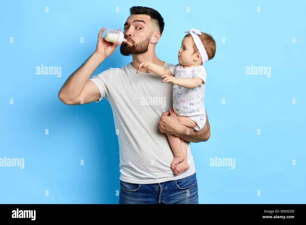 Young crazy father checking milk before giving it to kid. close up ...