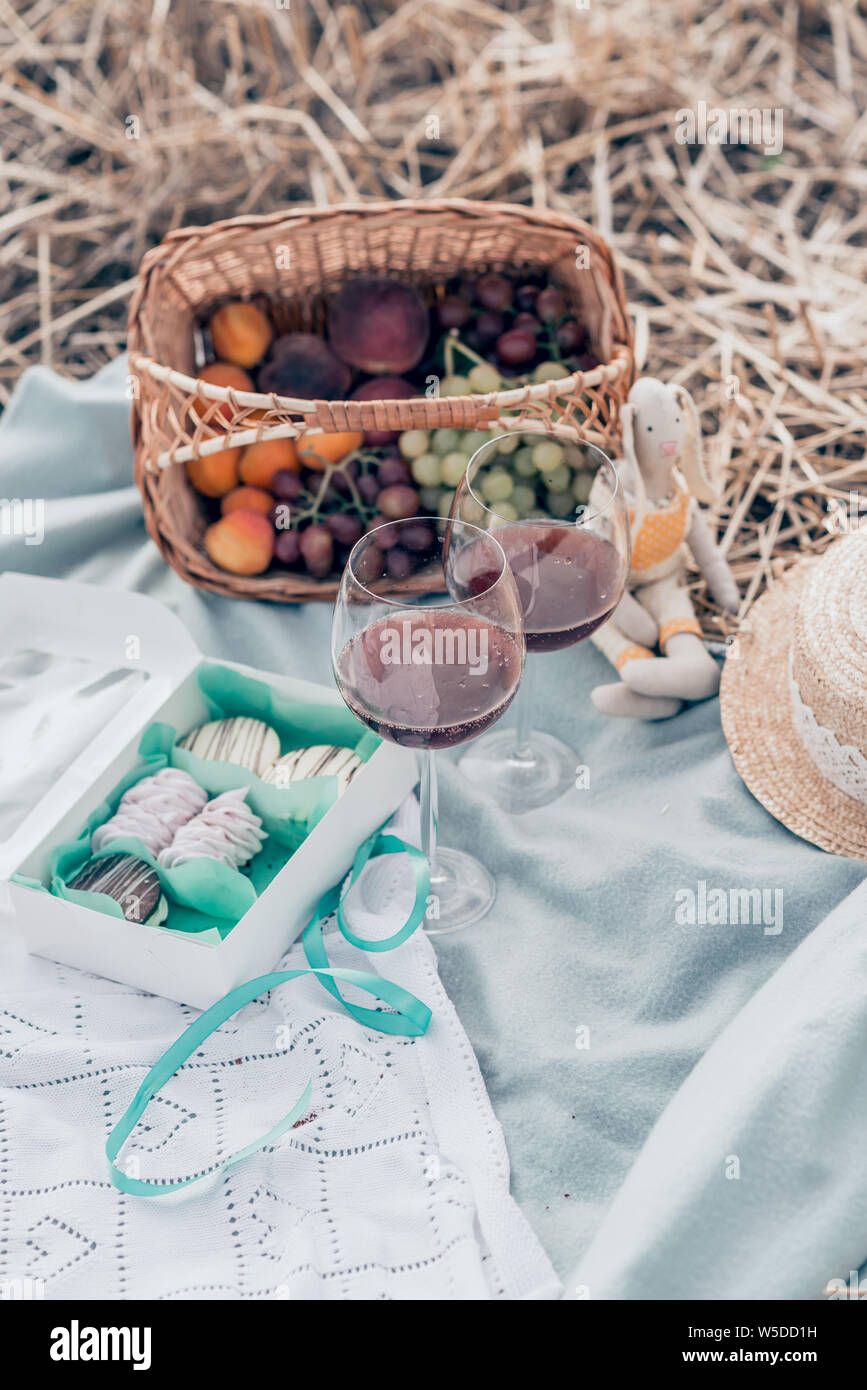 Two glasses of red wine, fruits and sweets on the sunset picnic. Top ...