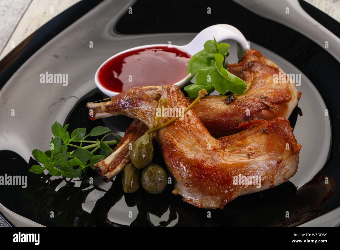 Roasted rabbit legs with cowberry sauce Stock Photo - Alamy