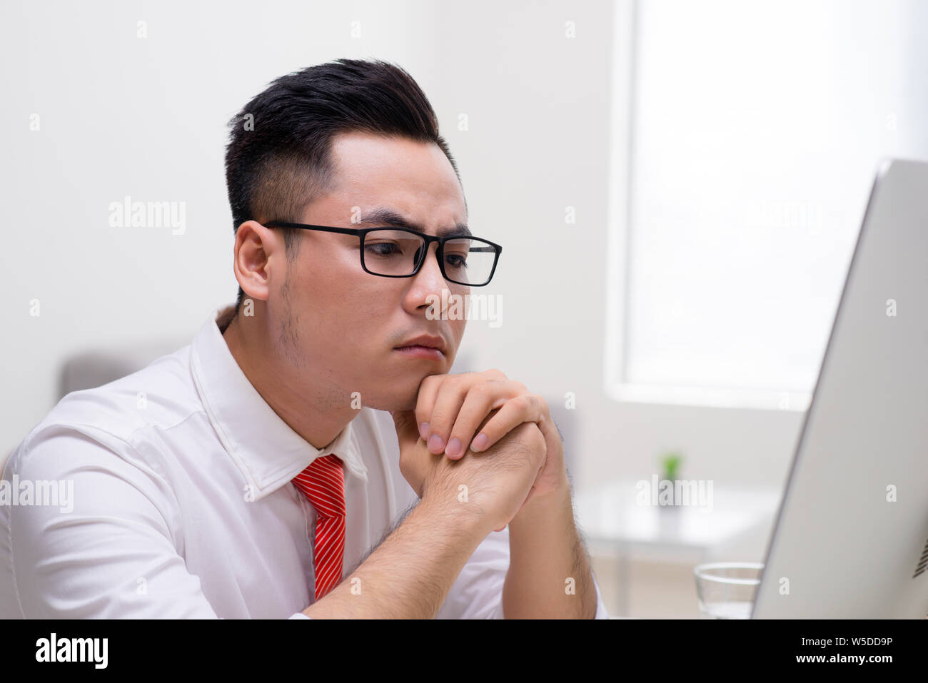 Young stylish worker at office working with computer and thinking how ...