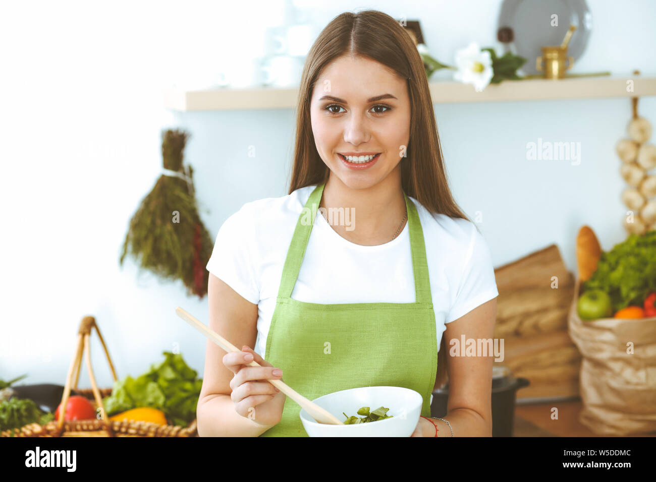 Young happy woman cooking in the kitchen. Healthy meal, lifestyle and ...