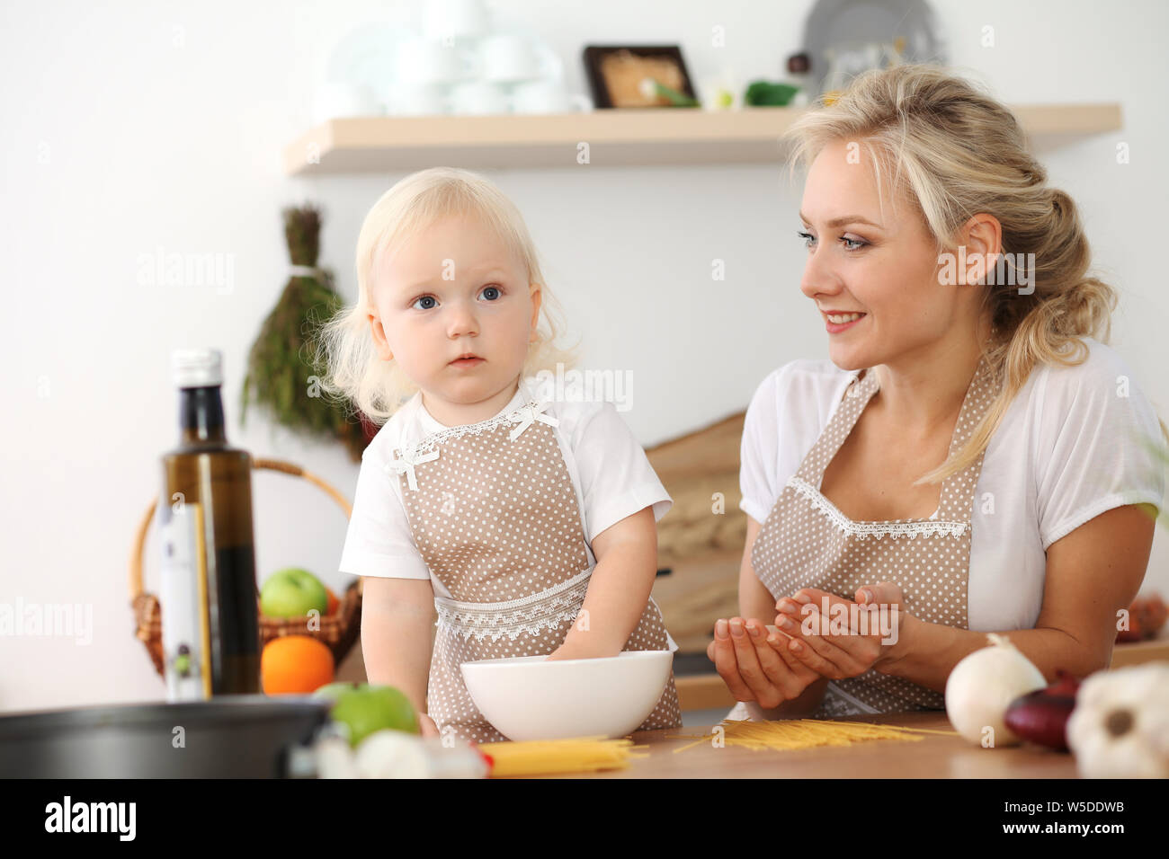 Happy mother and little daughter cooking in kitchen. Spending time all ...