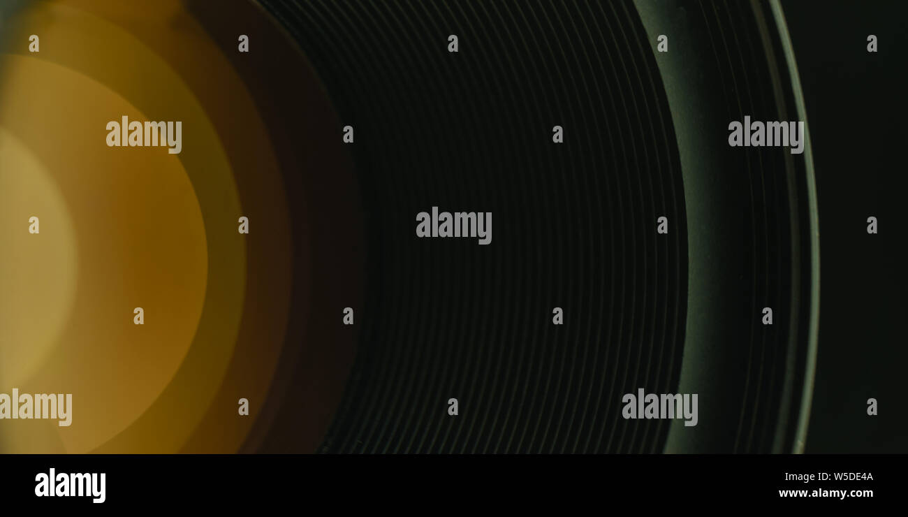 Beautiful camera lens with yellow light reflection of glass on a black ...