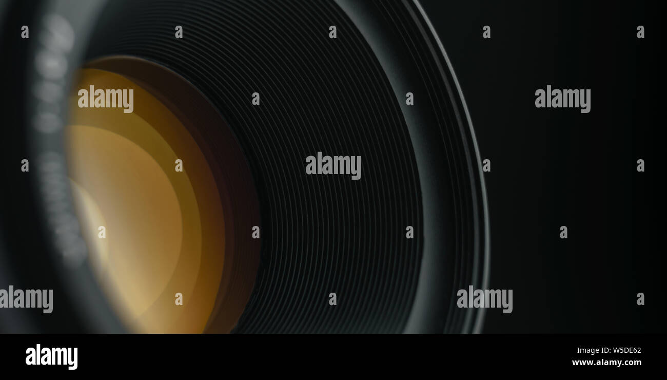 Beautiful camera lens with yellow light reflection of glass on a black ...