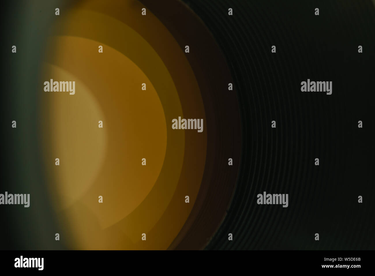 Beautiful camera lens with yellow light reflection of glass on a black ...