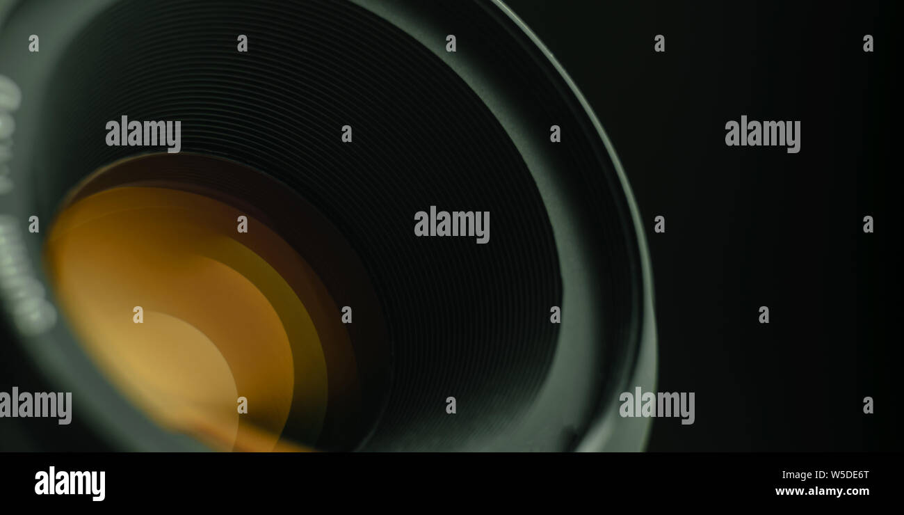 Beautiful camera lens with yellow light reflection of glass on a black ...