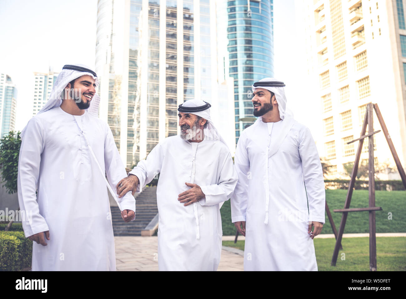 Three business men walking in Dubai wearing traditional emirati clothes ...