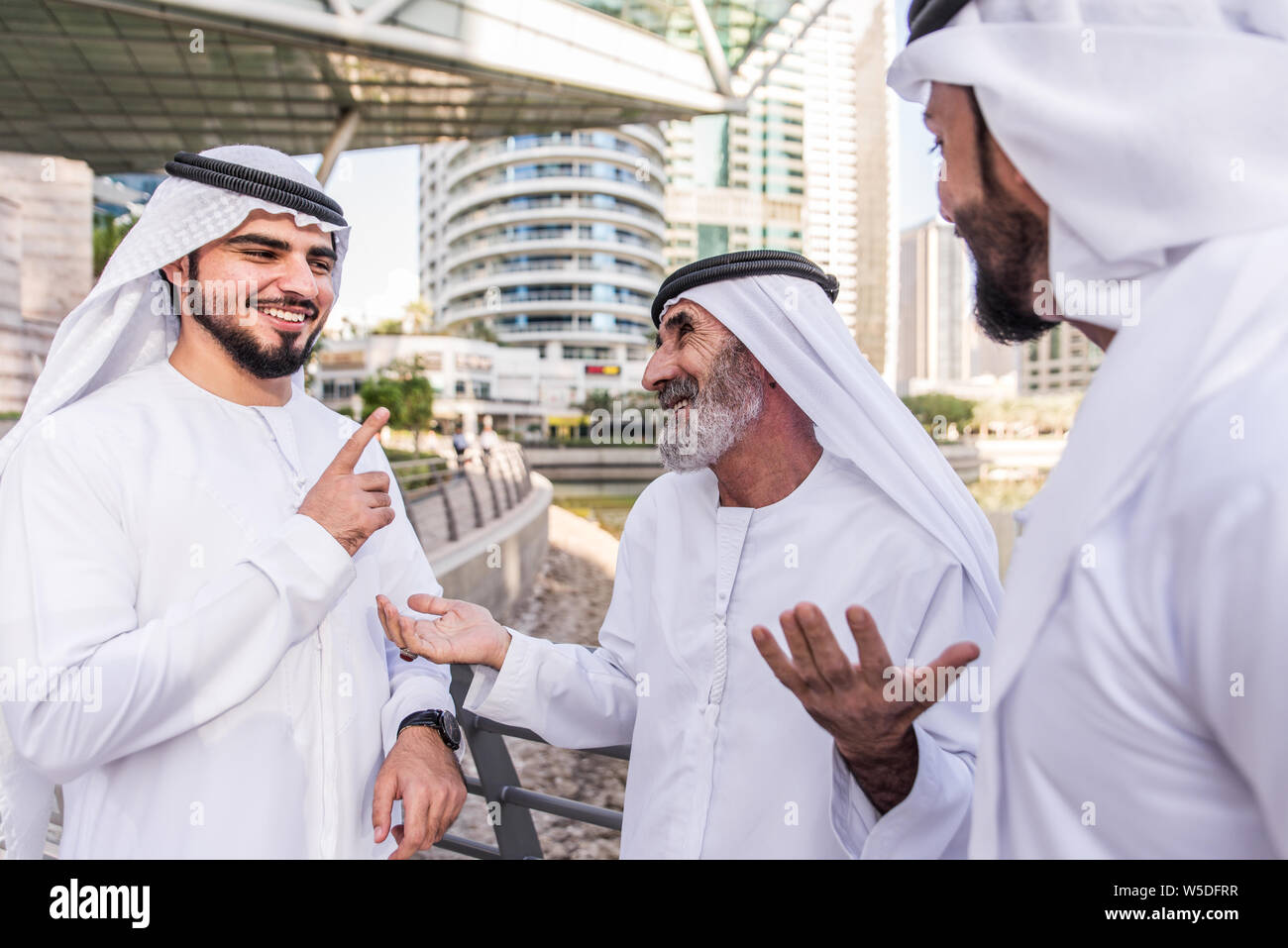 Three business men walking in Dubai wearing traditional emirati clothes ...