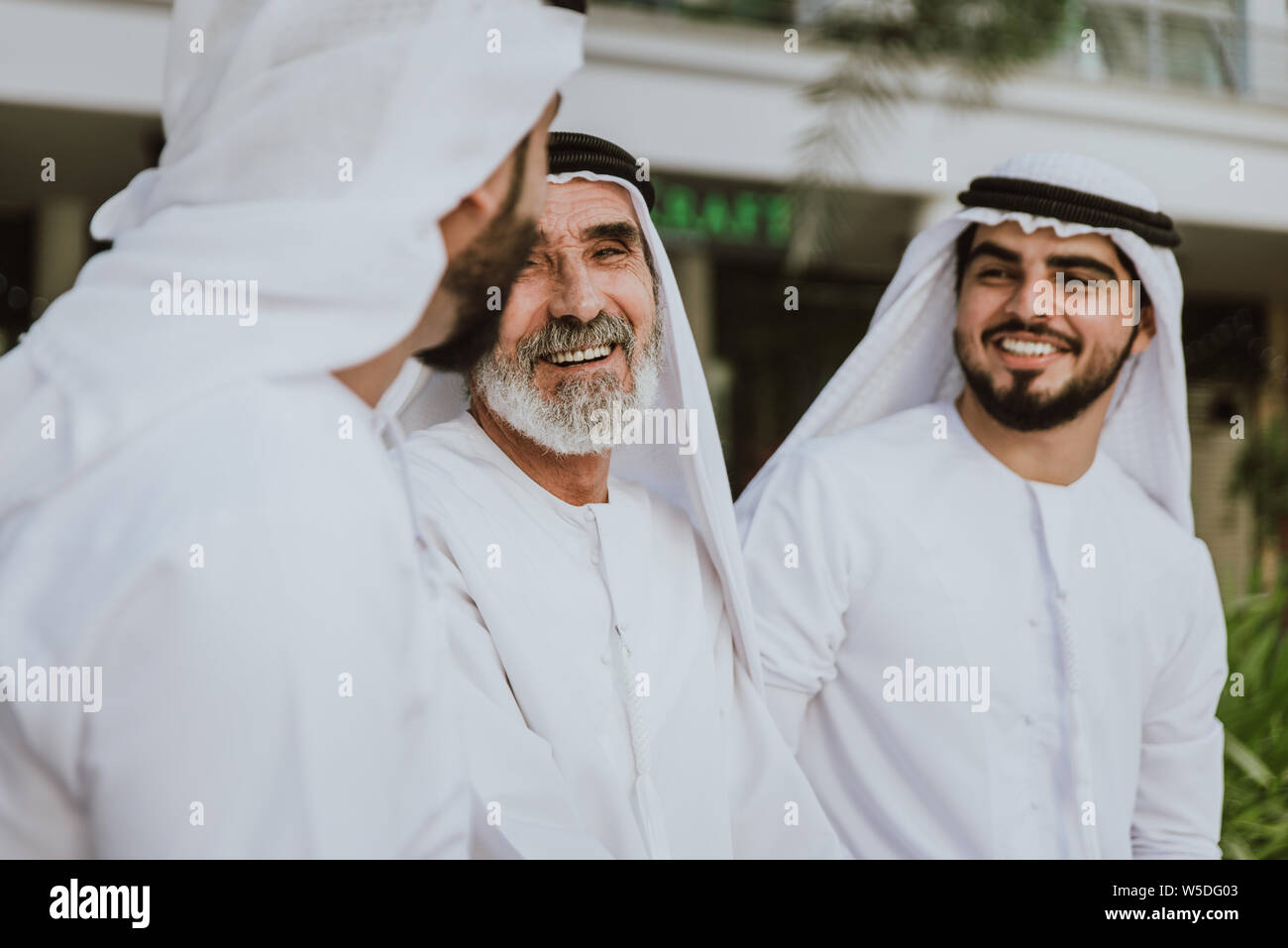 Three business men walking in Dubai wearing traditional emirati clothes ...