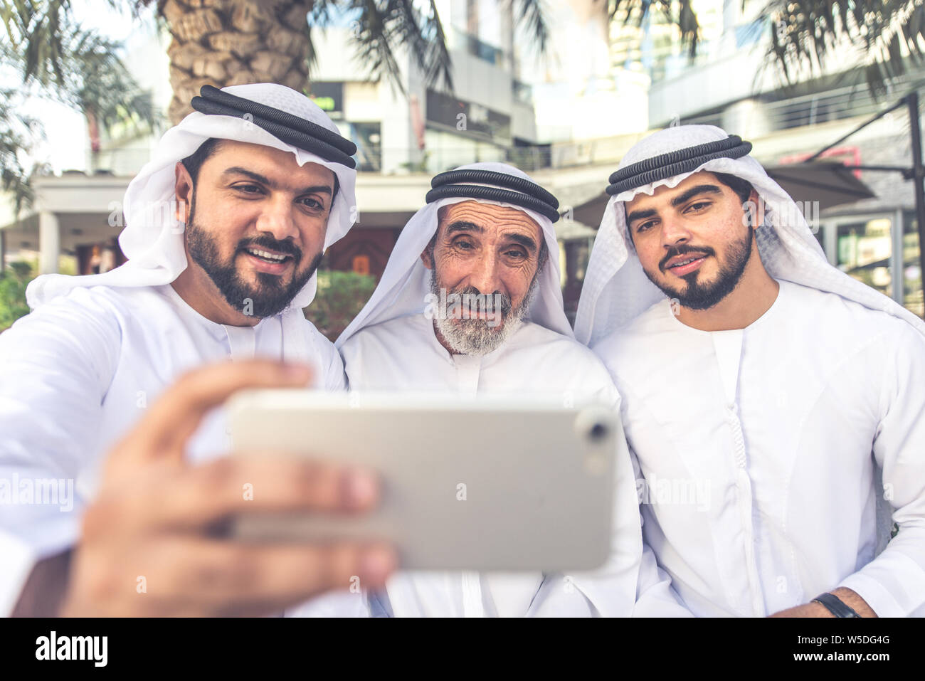Three business men walking in Dubai wearing traditional emirati clothes ...