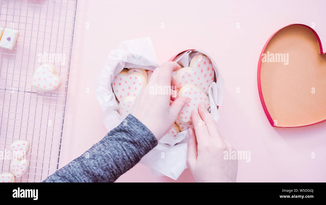 Flat lay. Packing heart shaped sugar cookies decorated with royal icing ...