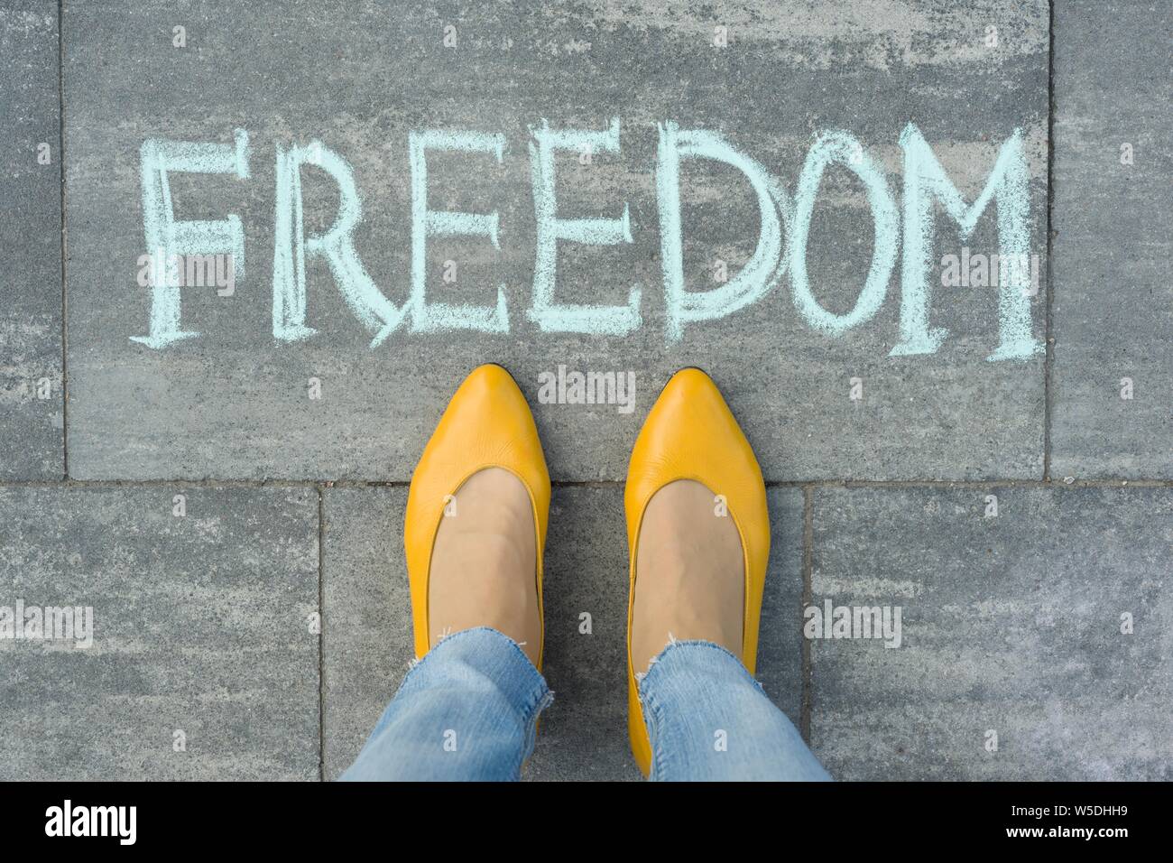 Female feet with text freedom written on grey sidewalk Stock Photo - Alamy