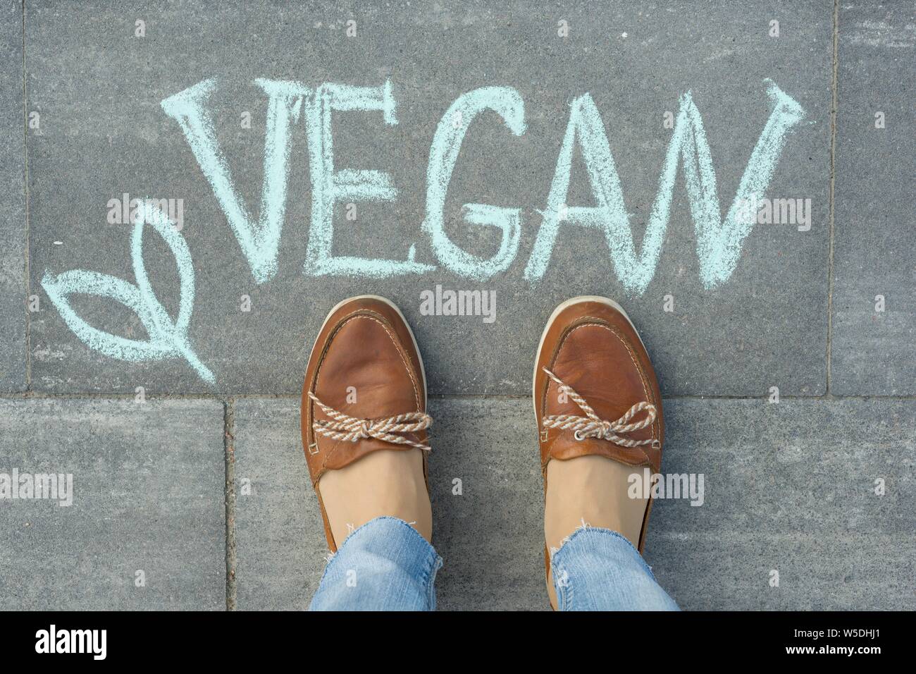 Female feet with text vegan written on grey sidewalk Stock Photo - Alamy
