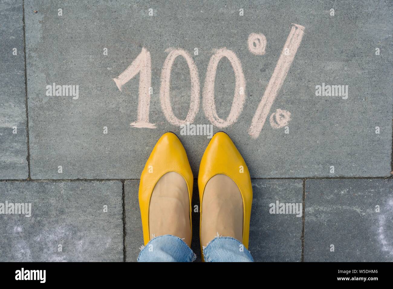 Female feet with text 100 percent written on grey sidewalk Stock Photo ...