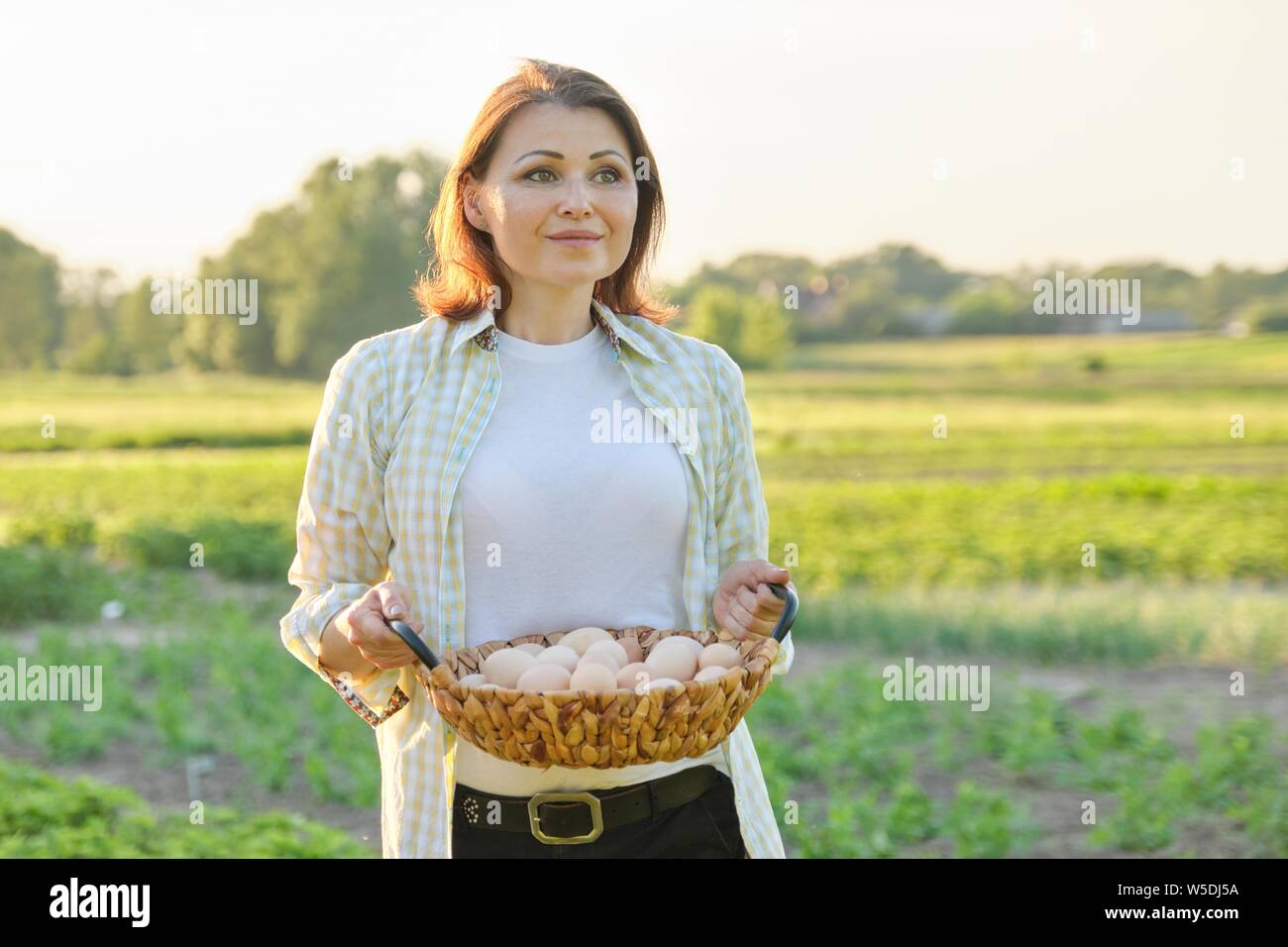 Outdoor portrait of farmer woman with basket of fresh chicken eggs ...