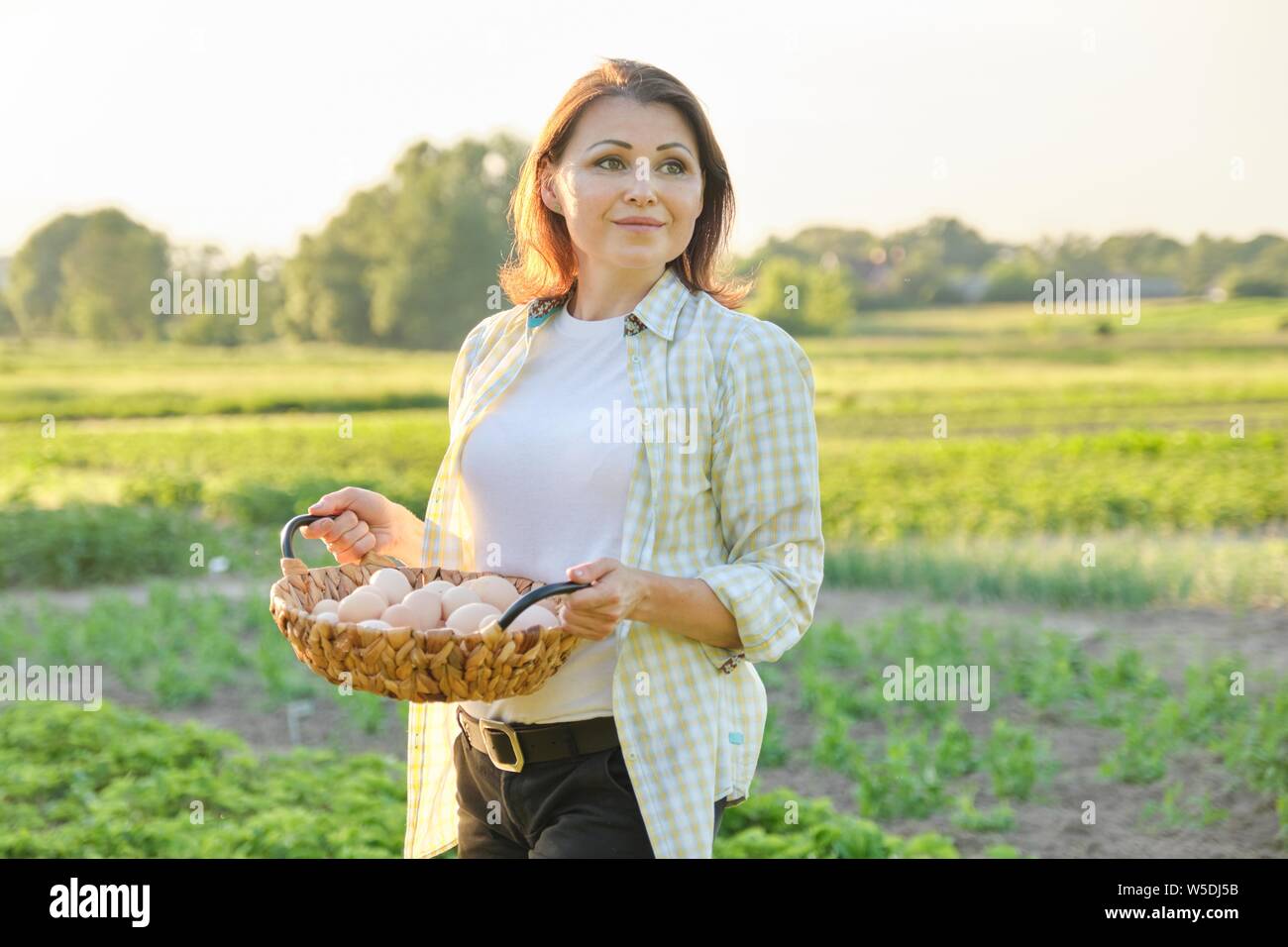 Outdoor portrait of farmer woman with basket of fresh chicken eggs ...