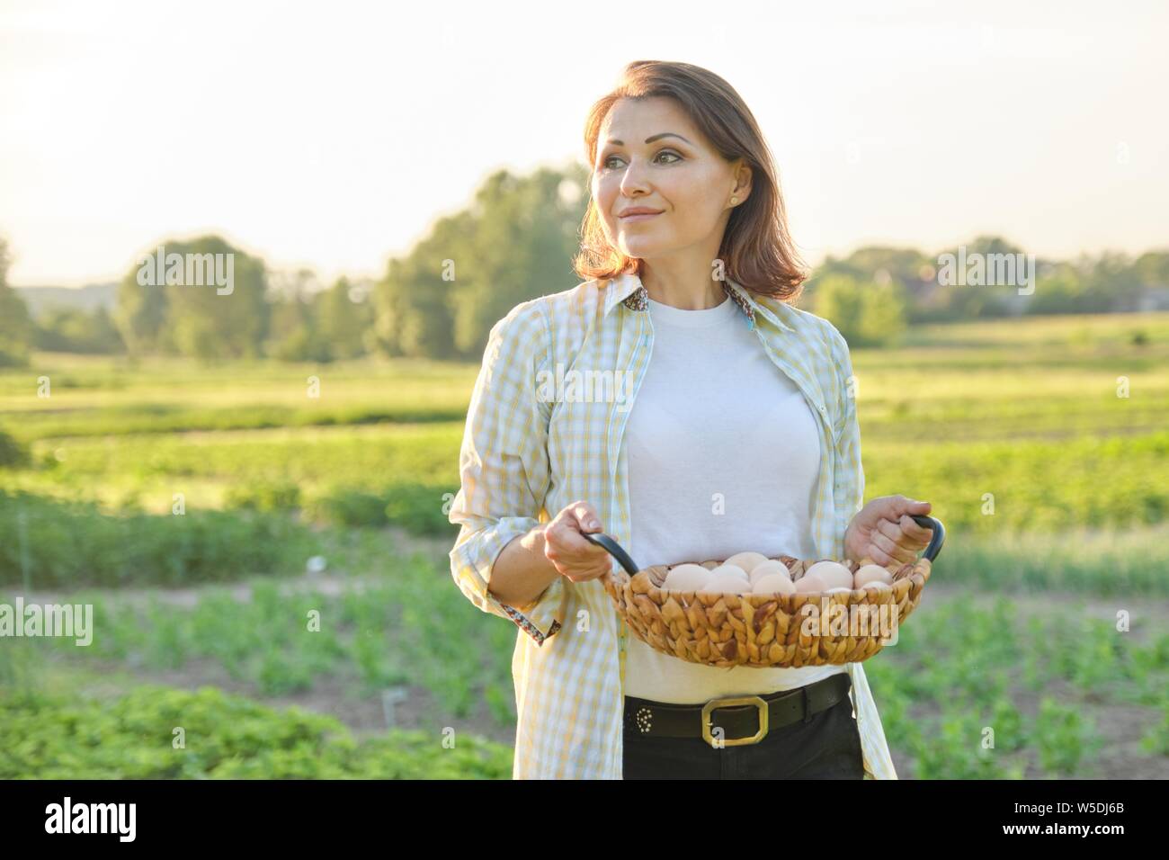 Outdoor portrait of farmer woman with basket of fresh chicken eggs ...