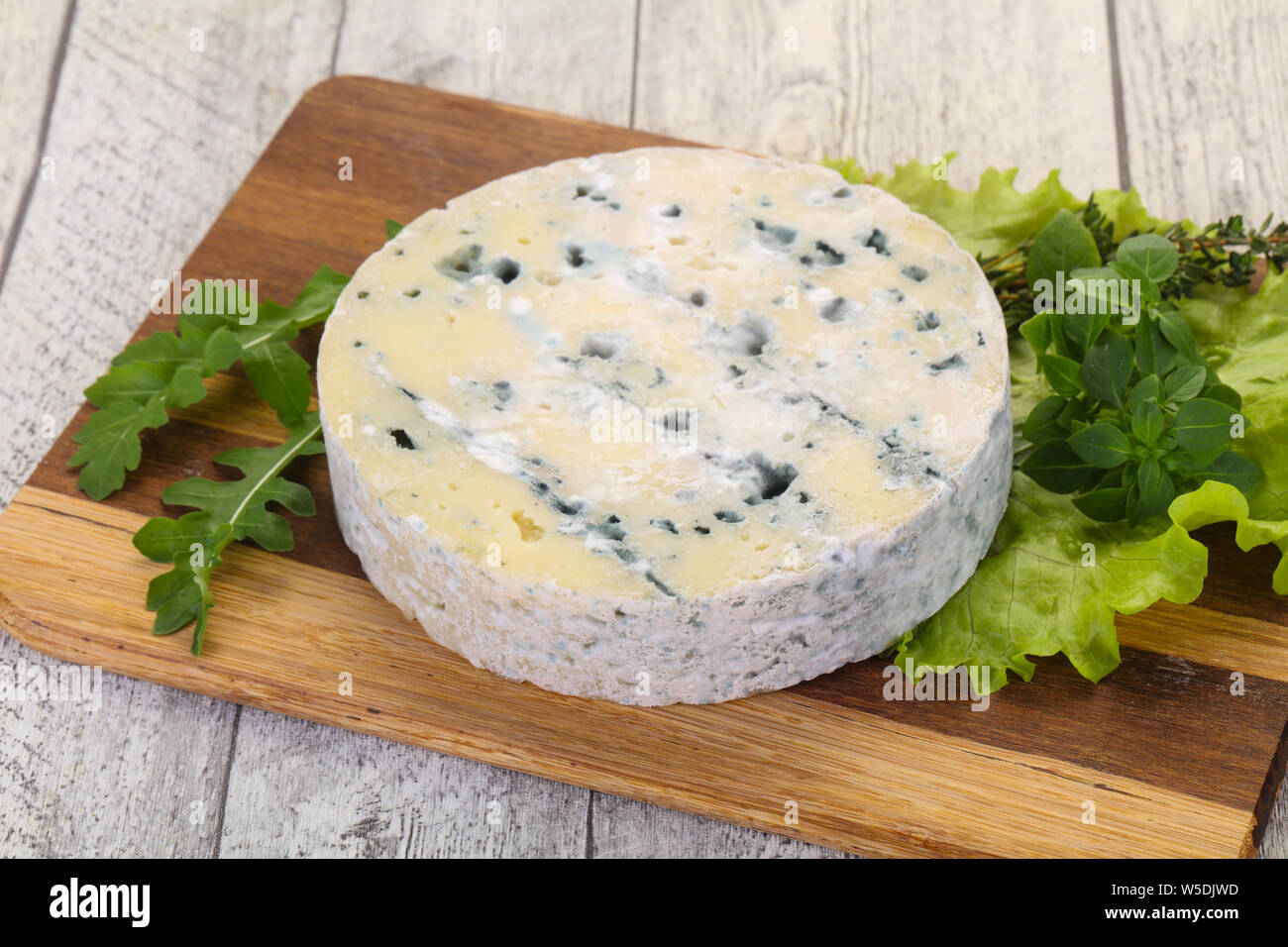 Round blue cheese with salad and basil Stock Photo - Alamy