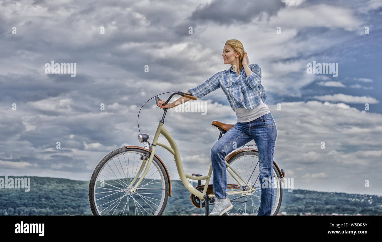 Health benefits of cycling. Woman rides bicycle sky background ...