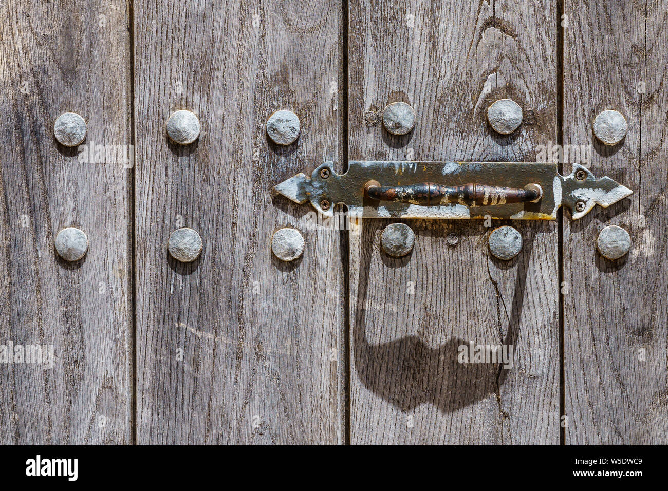 Handle of a weathered wooden door and it's shadow forming an abstract ...