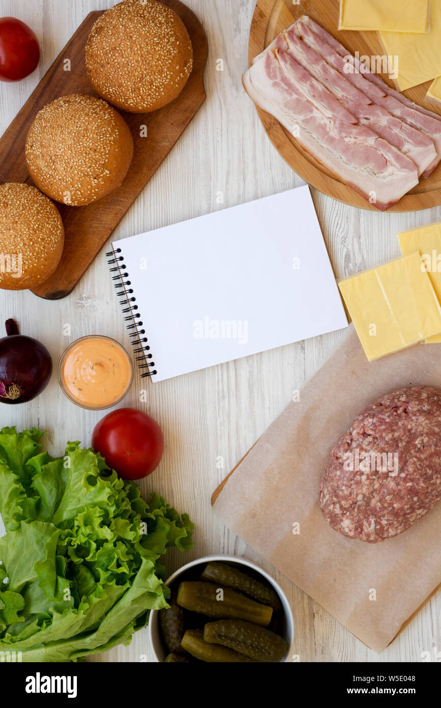 Cheeseburger ingredients on a white wooden surface, top view. Overhead ...