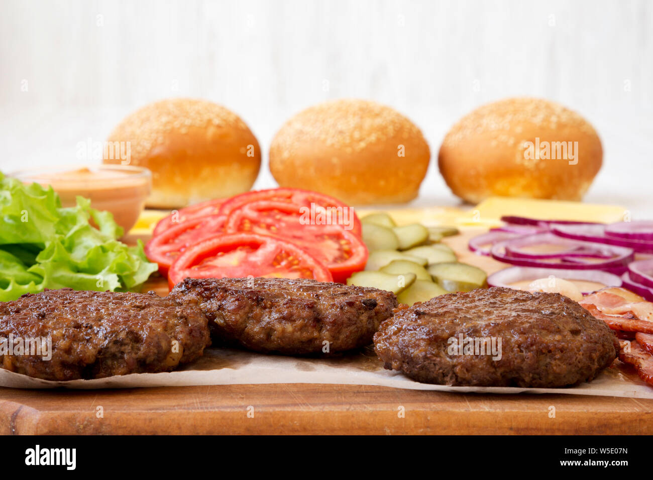 Burger ingredients on a white wooden background, side view. Close-up ...