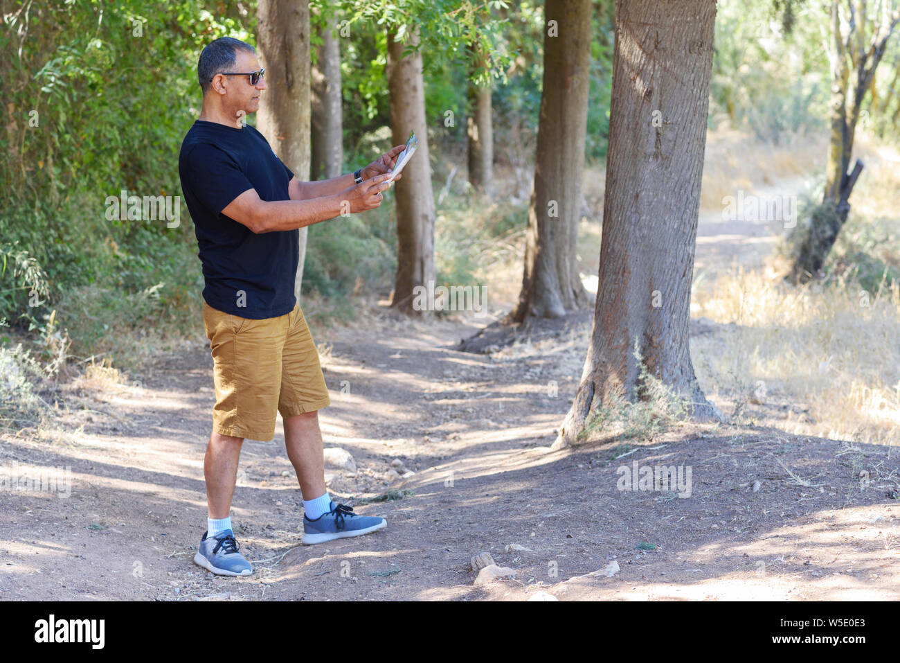 Senior man with map in forest. Portrait traveler old man searching ...