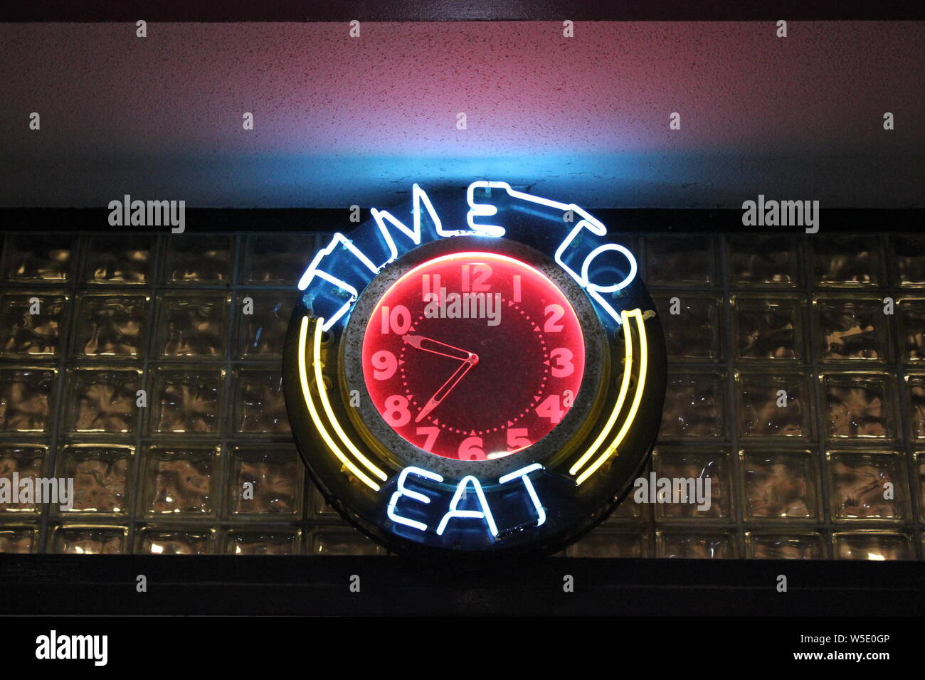 Bright neon sign of a clock and time to eat Stock Photo - Alamy