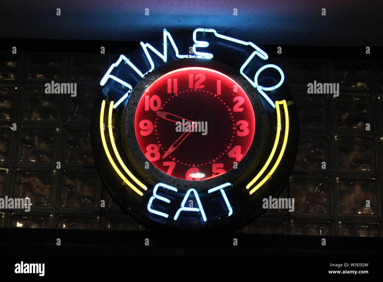 Bright neon sign of a clock and time to eat Stock Photo - Alamy
