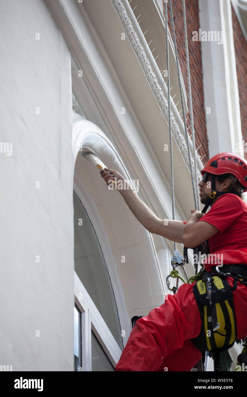 Painter in harness paints side of building hi-res stock photography and ...