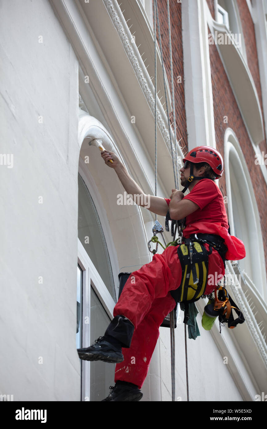 Painter in harness paints side of building hi-res stock photography and ...