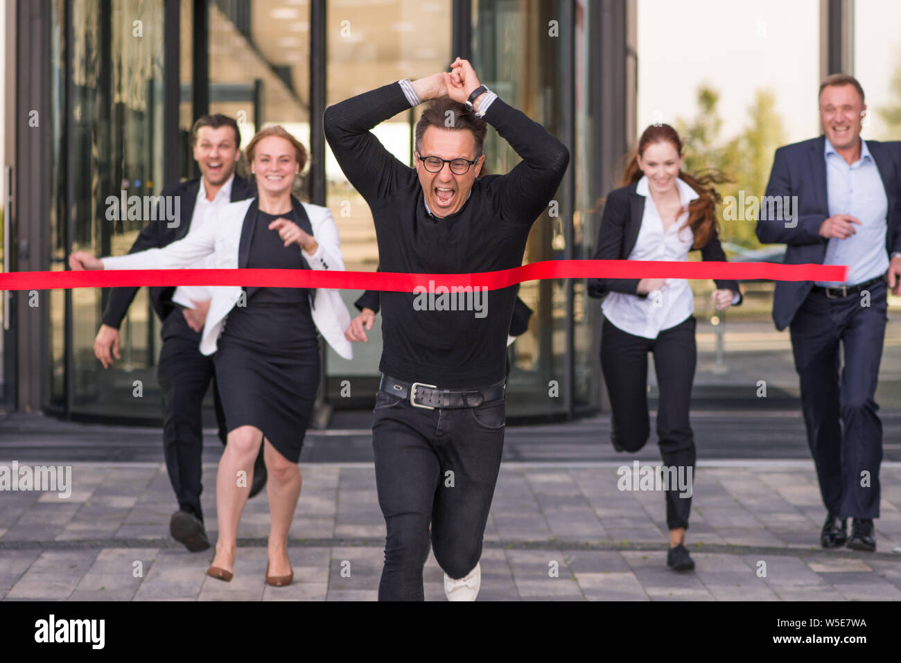 Group of happy business people running from office building crossing ...