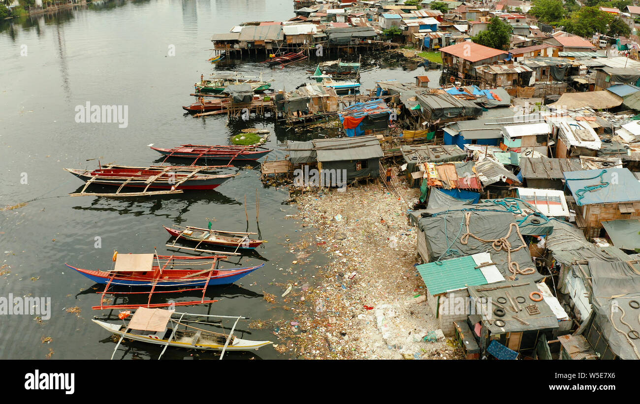 Slums in Manila on the bank of a river polluted with garbage, aerial ...