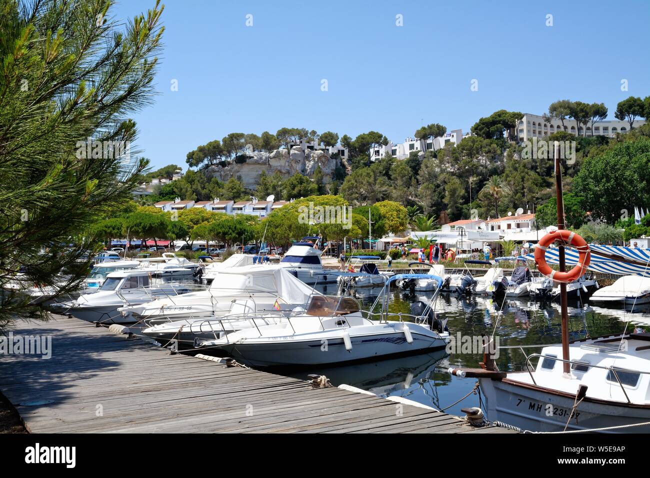 The small marina crowded with small boats in Cala Galdana on a hot ...