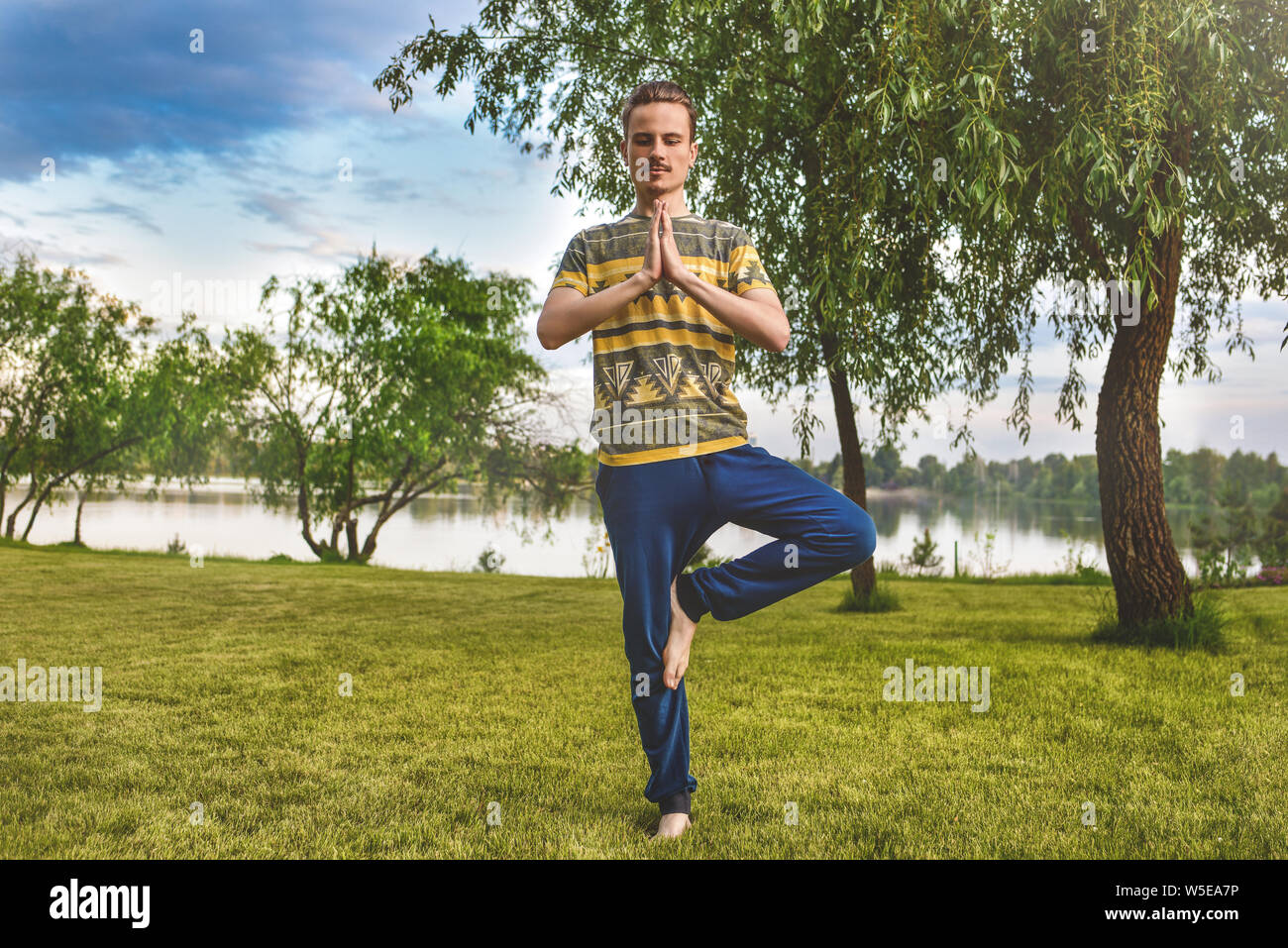 Fitness man doing exercise on one leg isolated in the park. enjoying ...