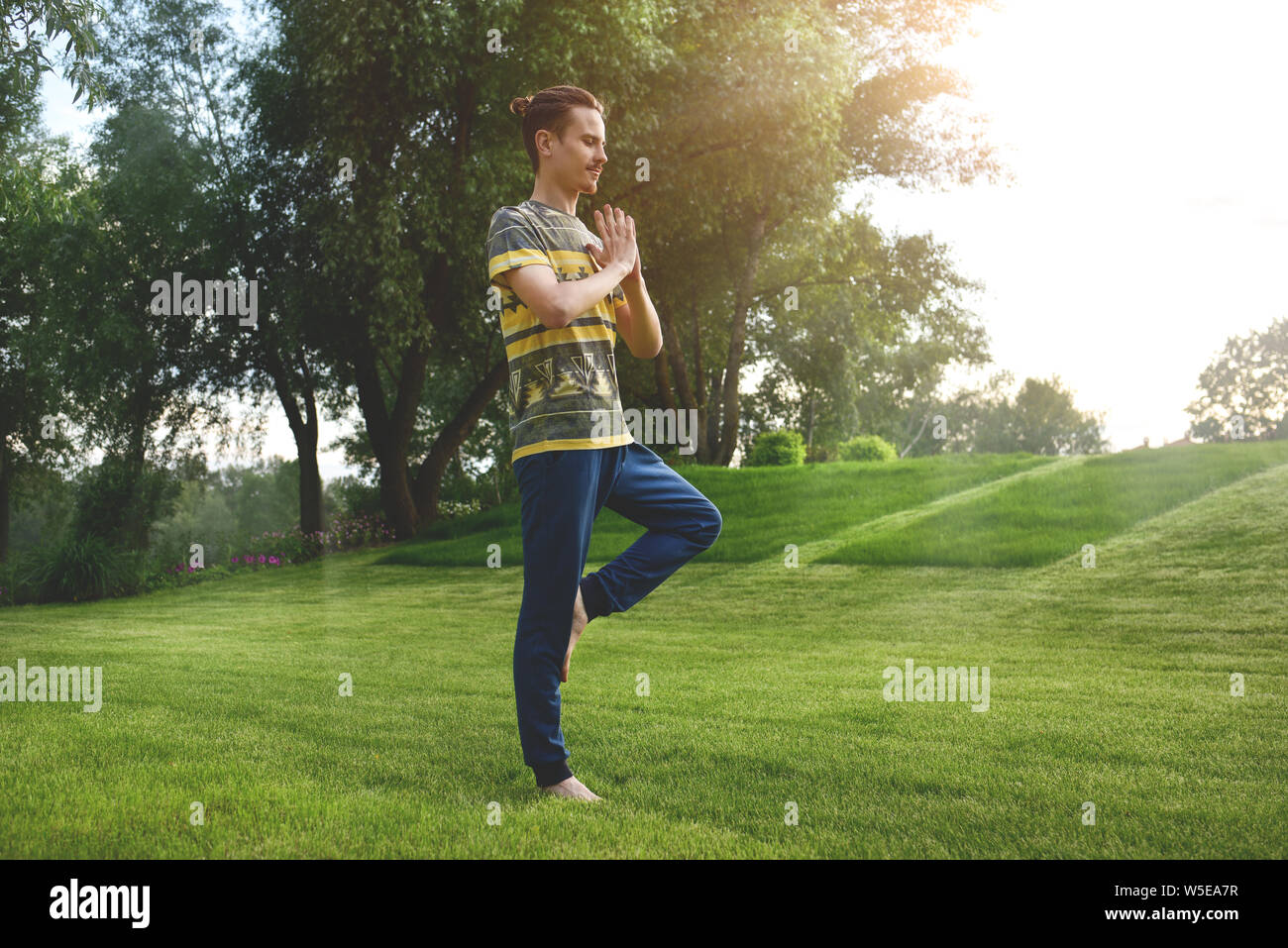 Fitness man doing exercise on one leg isolated in the park. enjoying ...