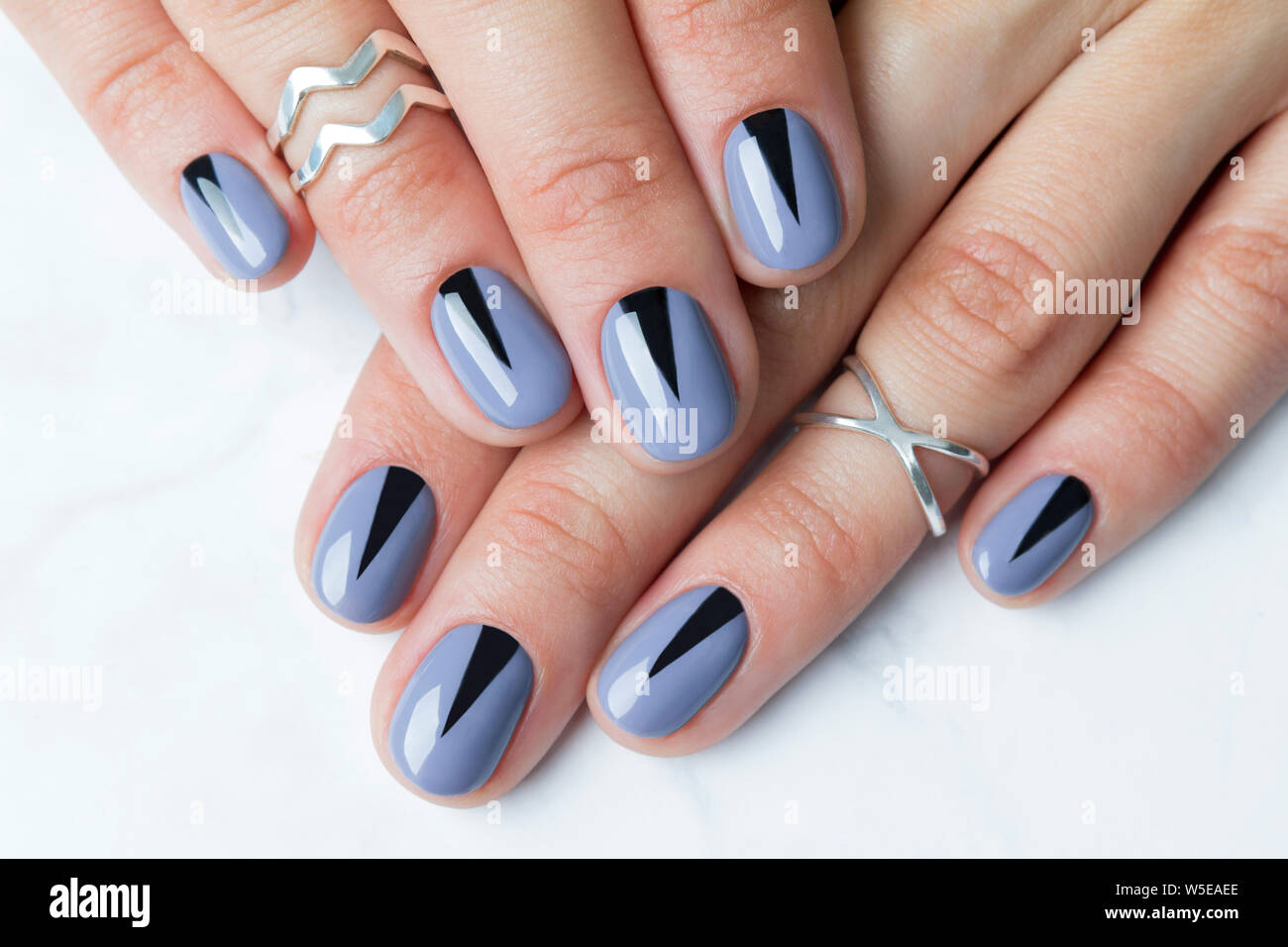 Two female hands with creative minimal manicure at white marble ...